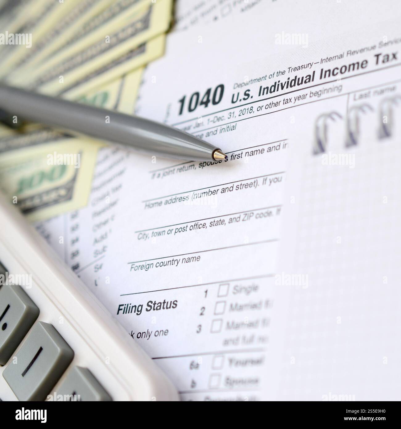 The pen, notebook, calculator, and dollar bills is lies on the tax form ...