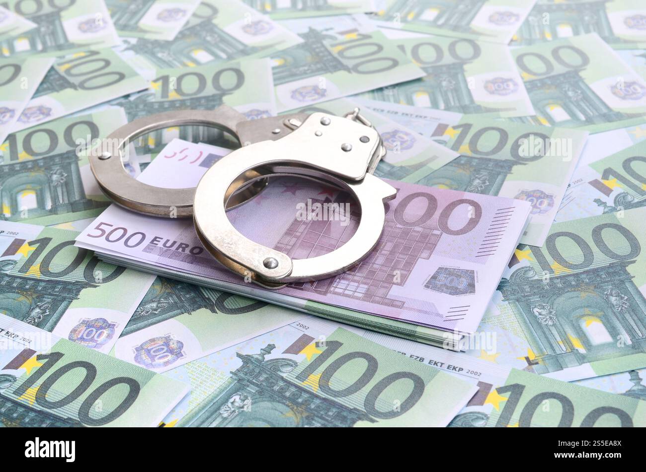 Police handcuffs lies on a set of green monetary denominations of 100 ...