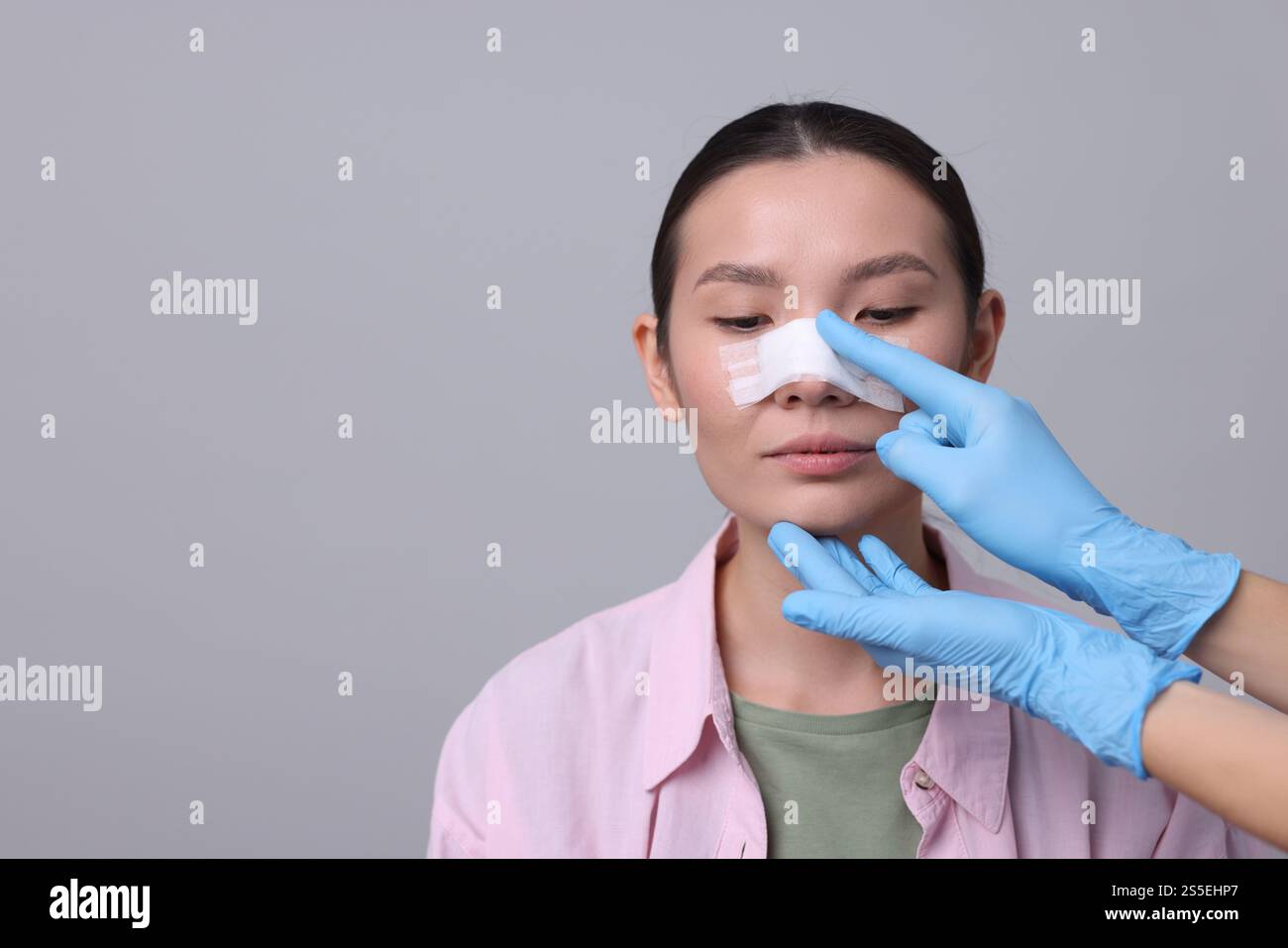 Doctor checking patient's nose after plastic surgery operation on light ...