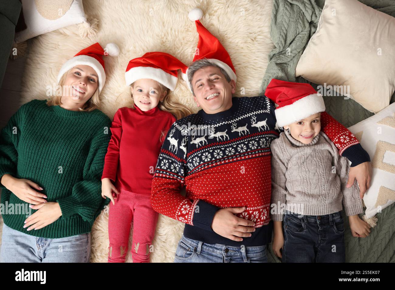Happy family in Santa hats lying on rug together, top view. Christmas ...