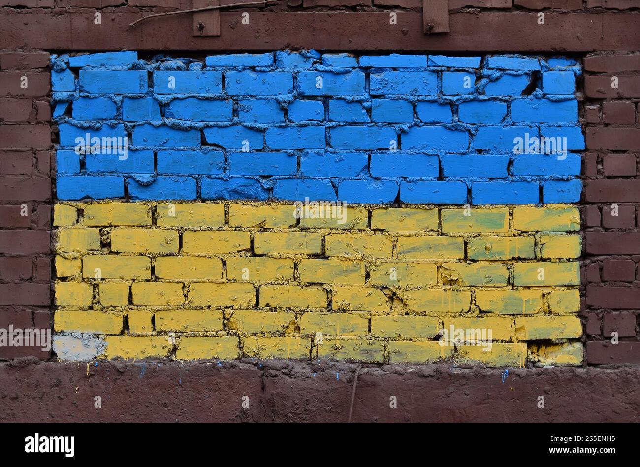 An old brick wall painted in the colors of the Ukrainian flag. Yellow ...