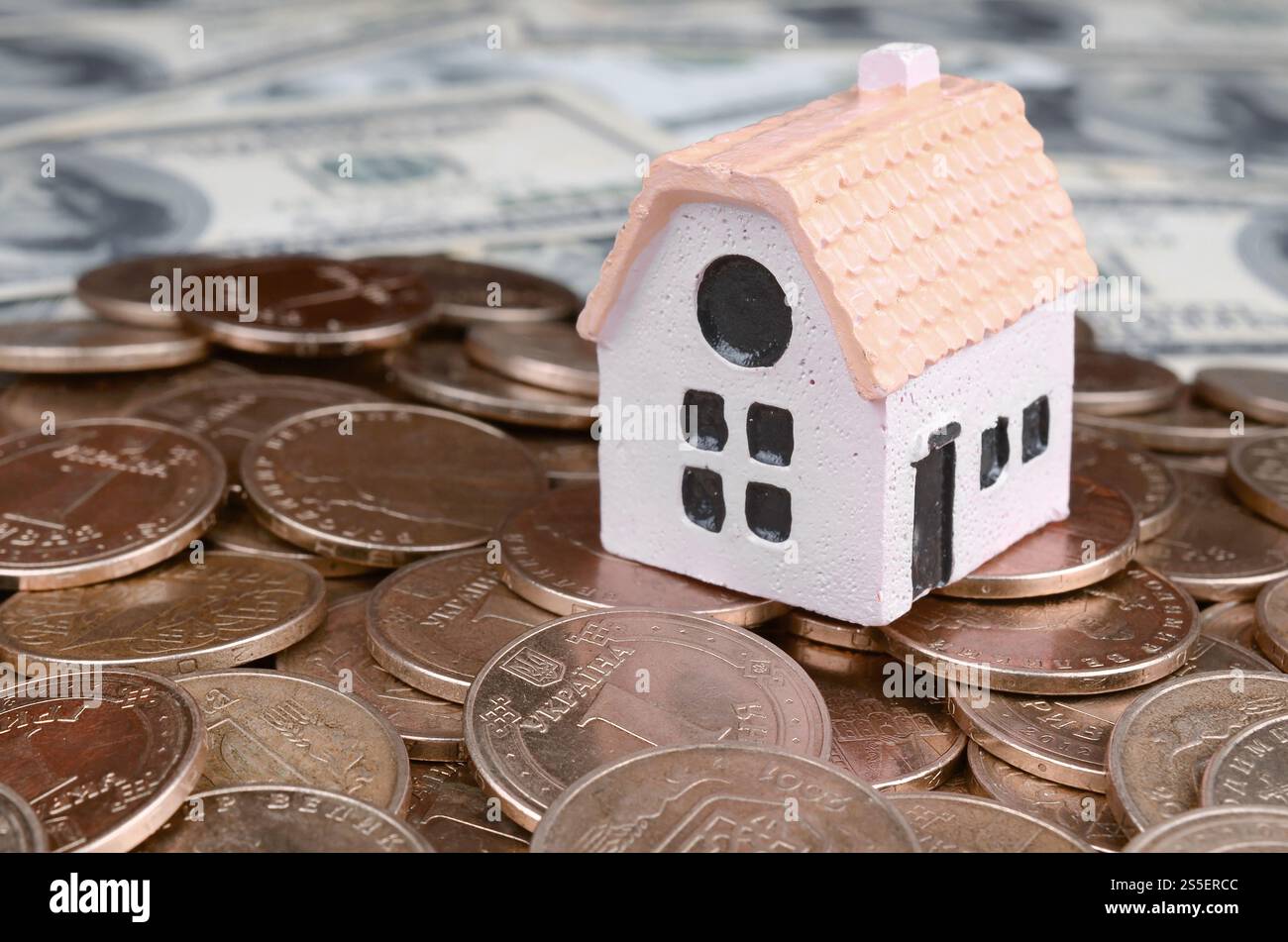 Mini house model on big coins stack on many dollar bills as background ...