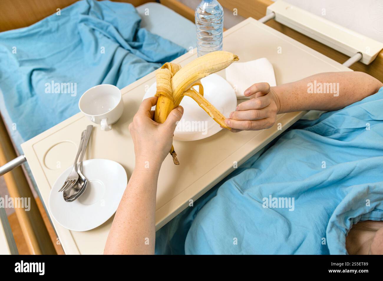 sick woman peels banana in homecare hospital bed at home Stock Photo ...