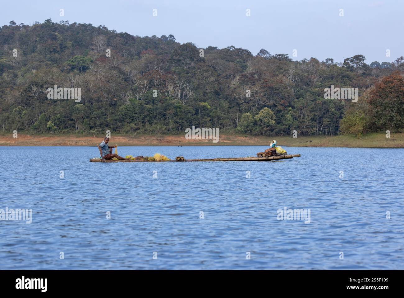 A fisherman navigating a traditional bamboo raft across the serene ...