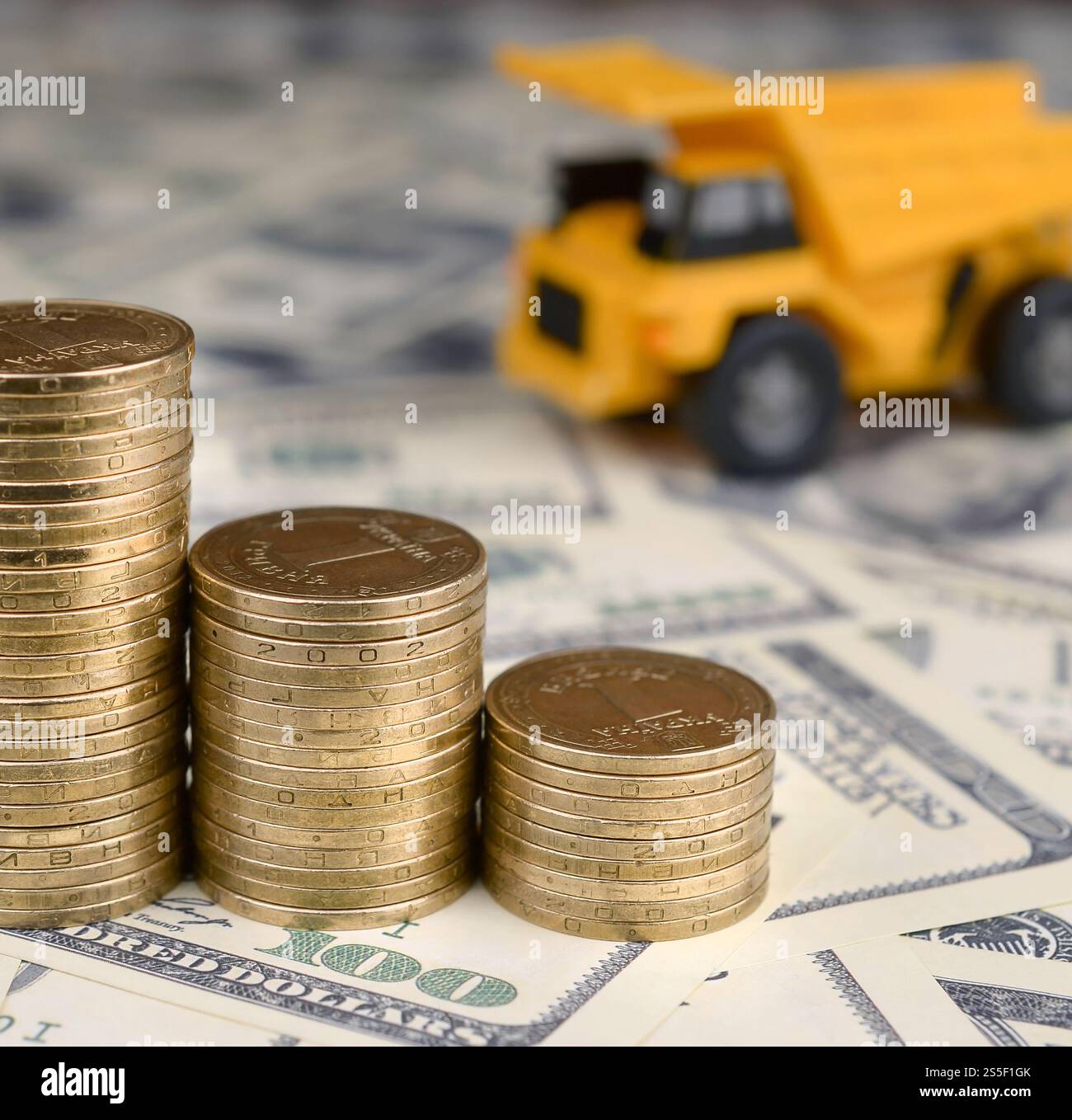 Dump truck toy and stacks of gold coins on background of many hundred ...