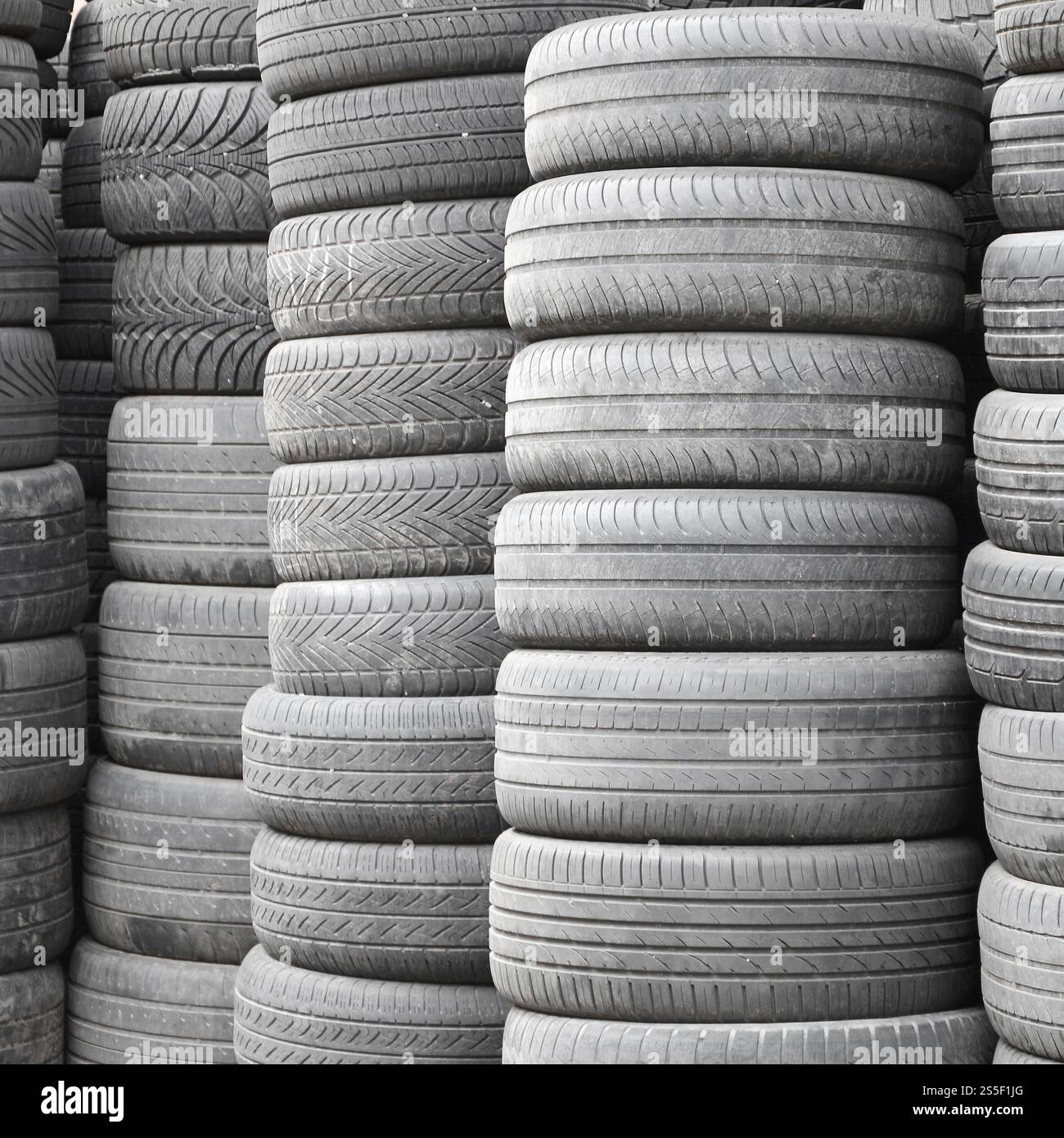 Old used tires stacked with high piles in secondary car parts shop ...