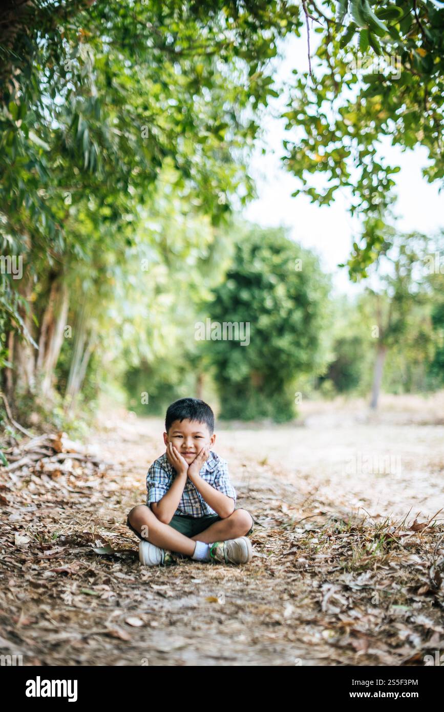 Happy boy sitting and thinking alone in the park Stock Photo - Alamy