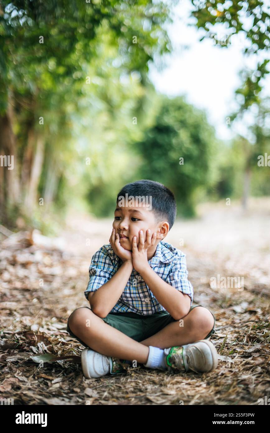 Happy boy sitting and thinking alone in the park Stock Photo - Alamy