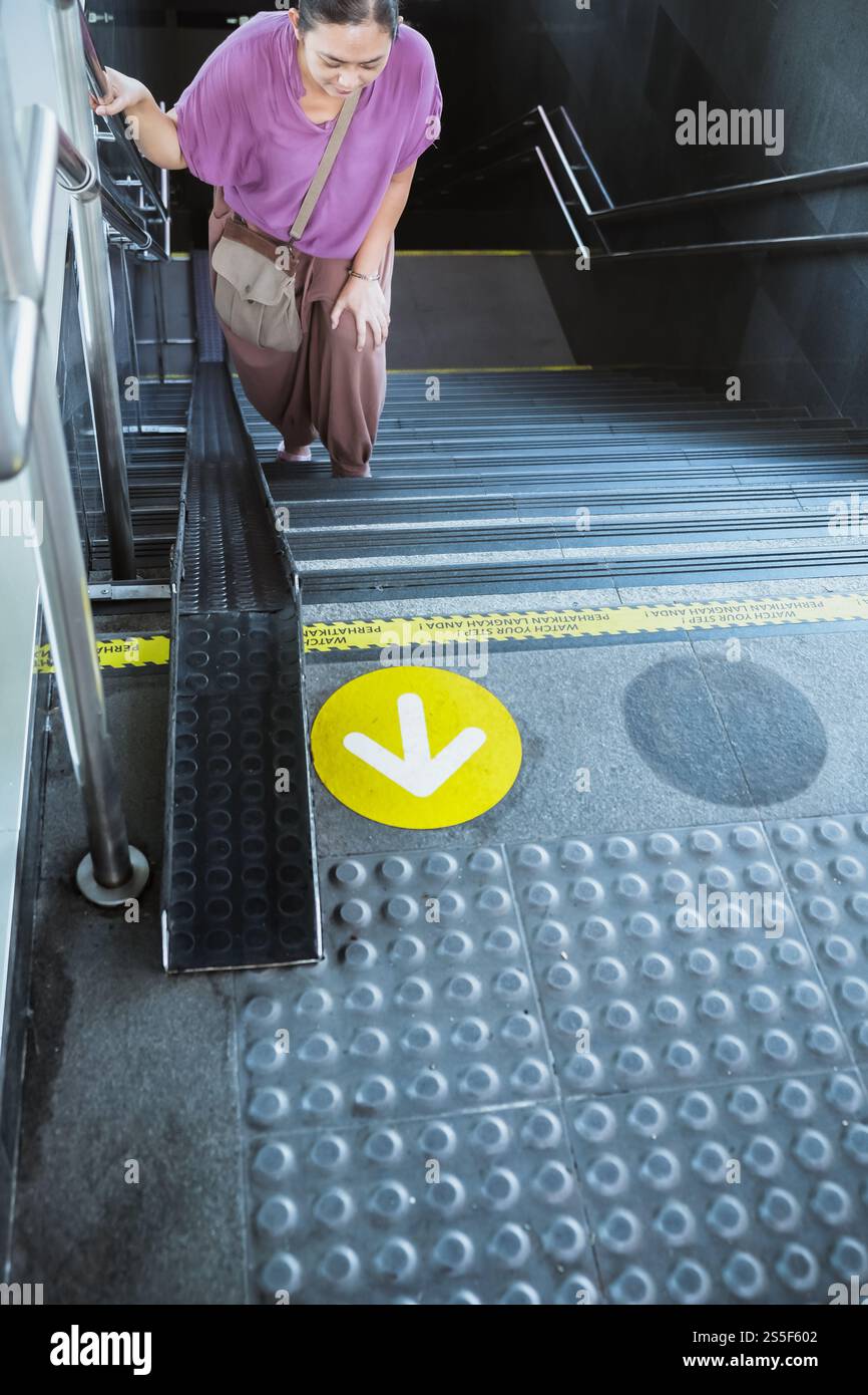 Asian adult woman climbing up the subway station steep stairs with ...