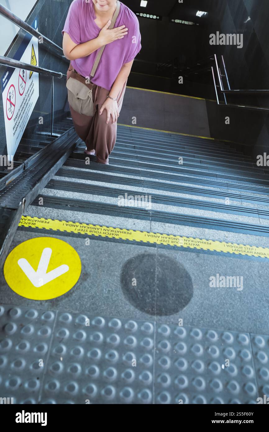 Asian adult woman climbing up the subway station steep stairs with ...