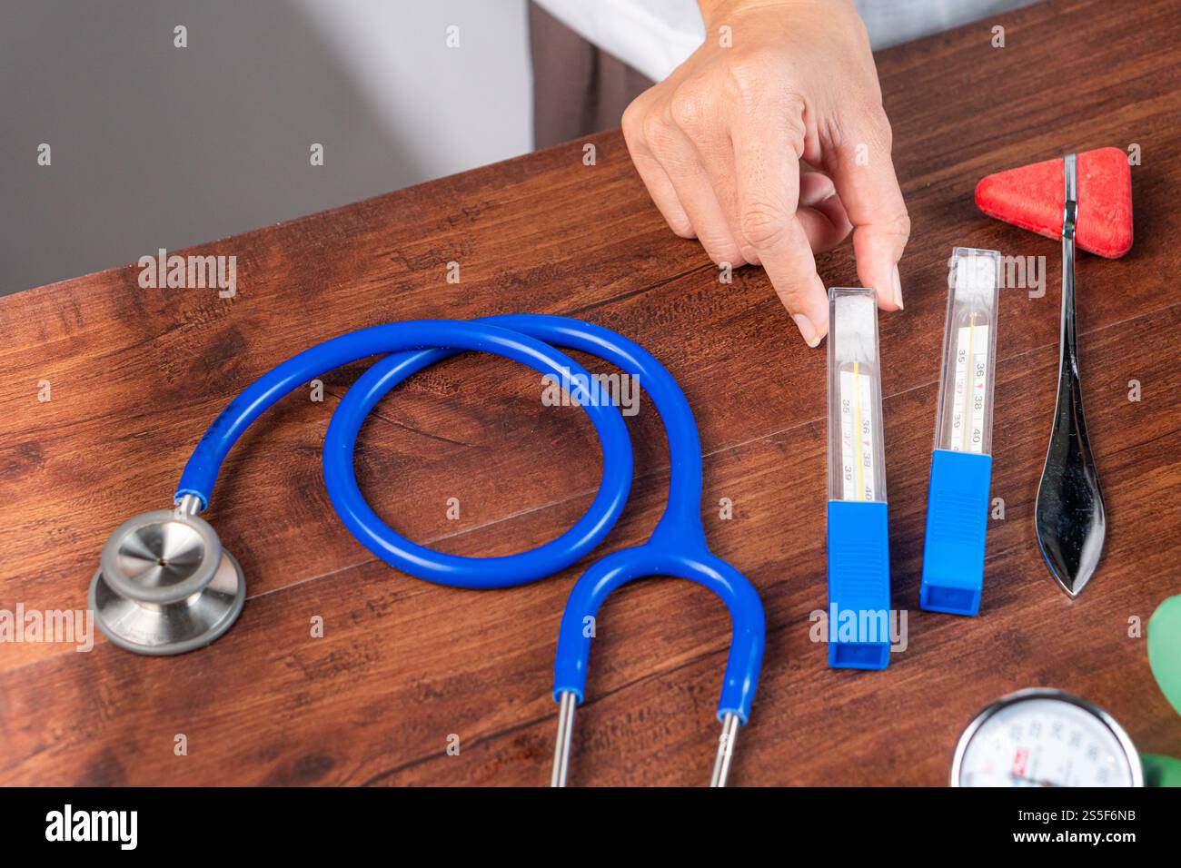 A close-up view of a wooden table with a stethoscope, two blue test ...