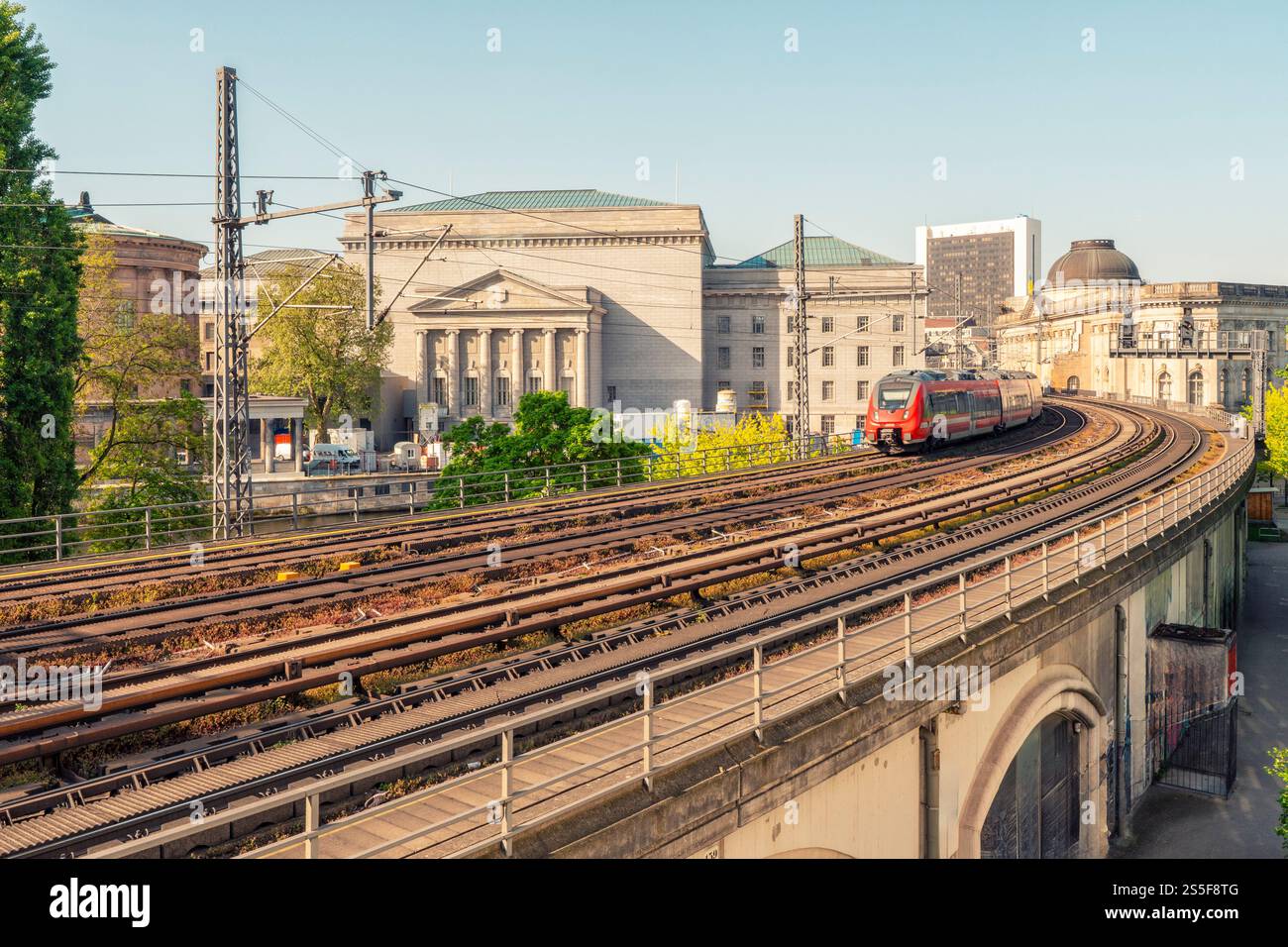 Red train moving on elevated tracks in Museums island with classic architecture of Bode and ...