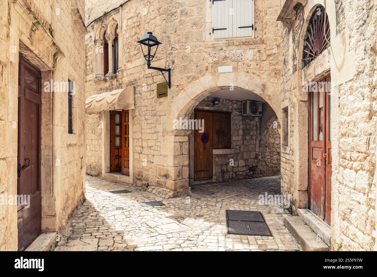 Cobblestone alley with historical stone buildings and an arched ...