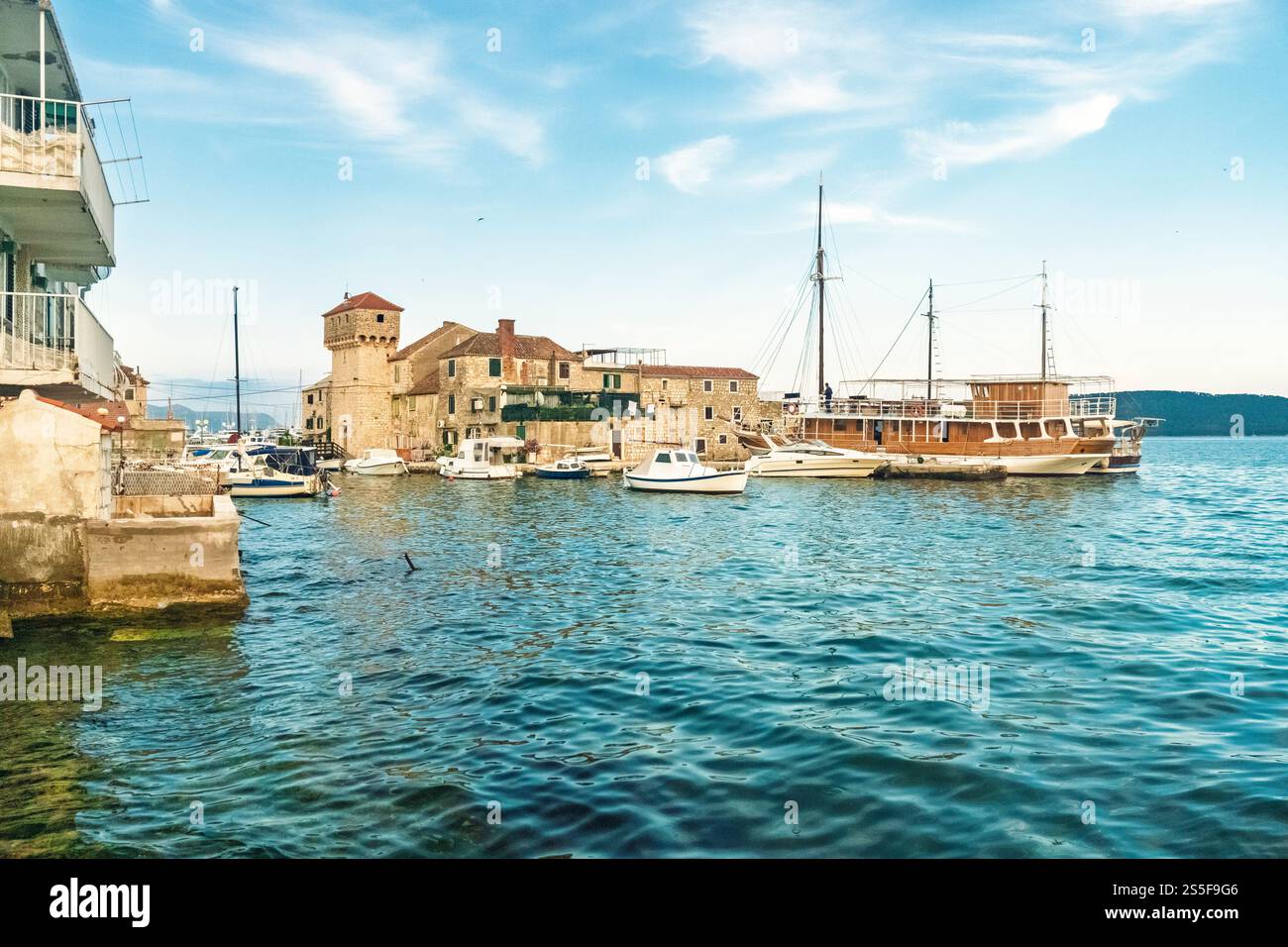 Sunset view of a peaceful harbor with a classic sailboat, smaller boats ...