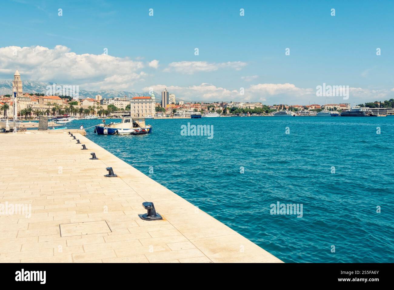 Sunny day at a lively seaside promenade with views of boats, city ...
