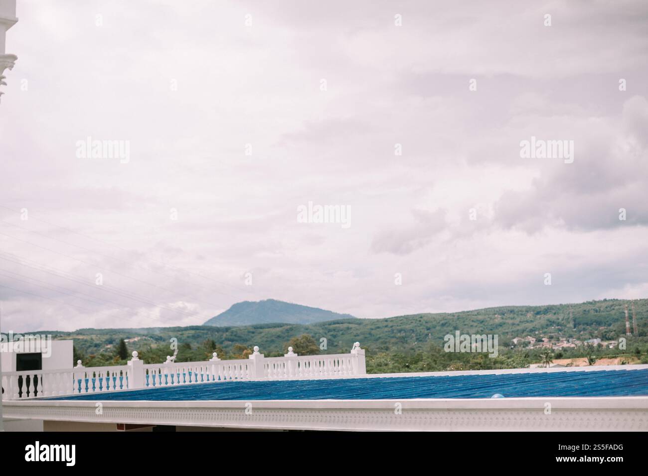 A rooftop with a white balustrade overlooks a tranquil landscape with a ...
