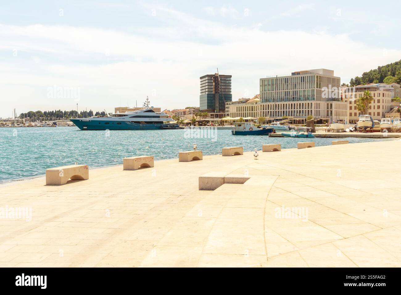 Scenic view of a waterfront promenade with modern buildings and a yacht ...