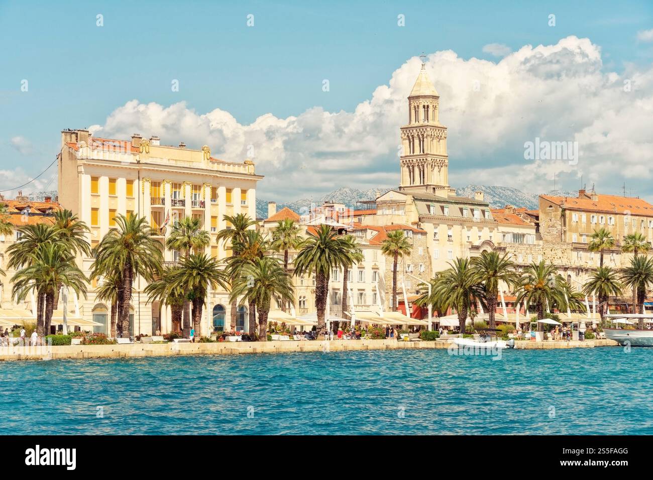 Palm trees line the waterfront promenade in front of historic buildings ...