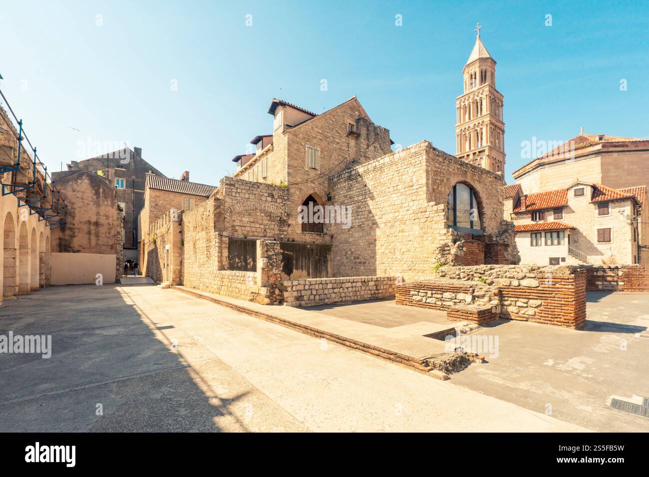 Sunlit view of an old stone church with a bell tower of St Domnius ...