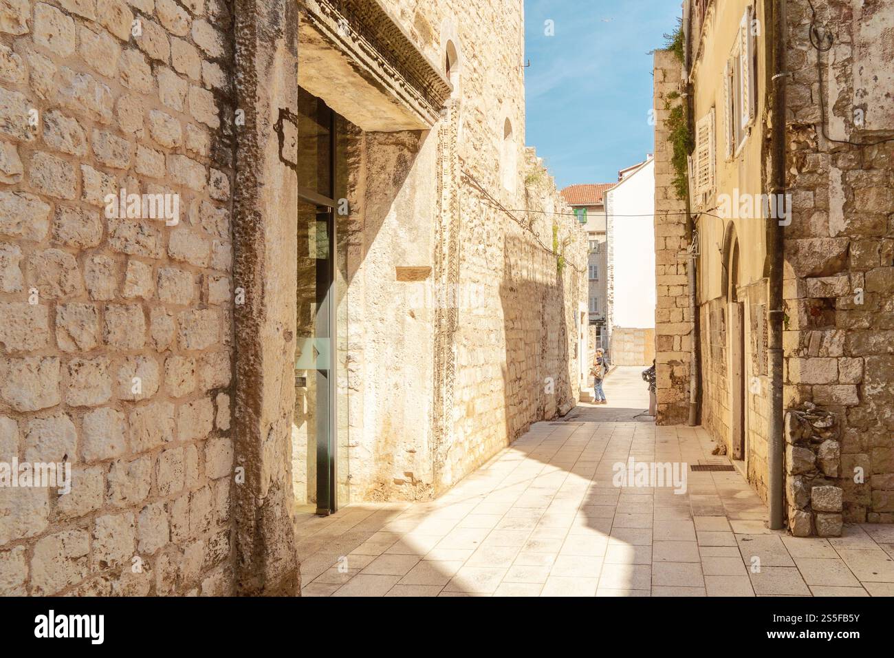 Narrow cobblestone street with ancient stone buildings and a clear blue ...