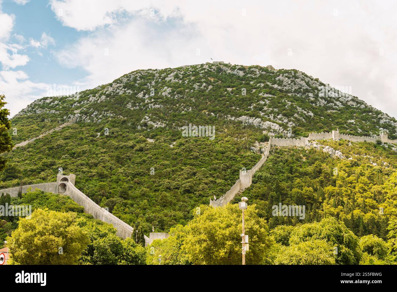 A mountain with a historical stone wall of Ston city winding up its ...