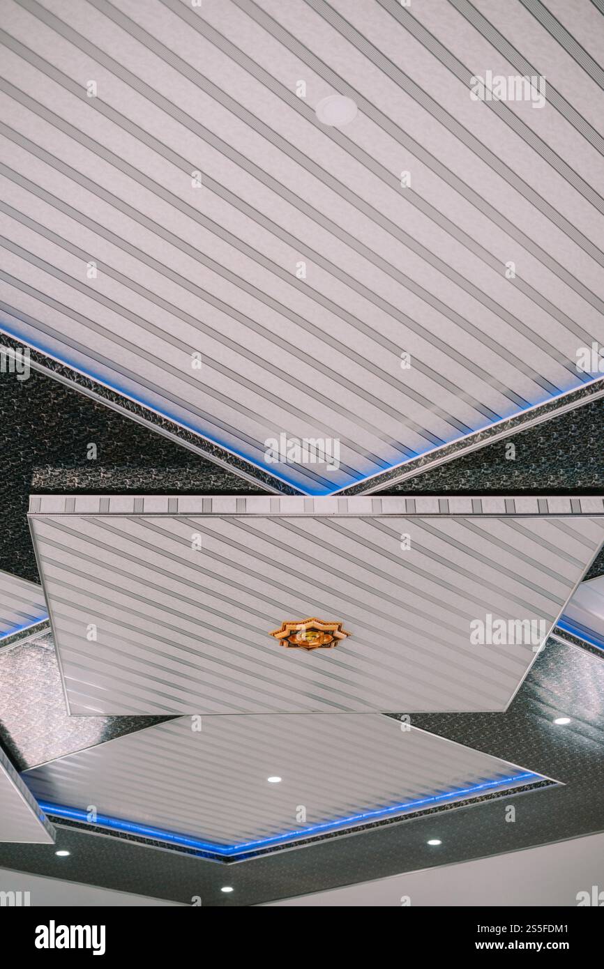 A contemporary ceiling featuring geometric panels, integrated lighting ...