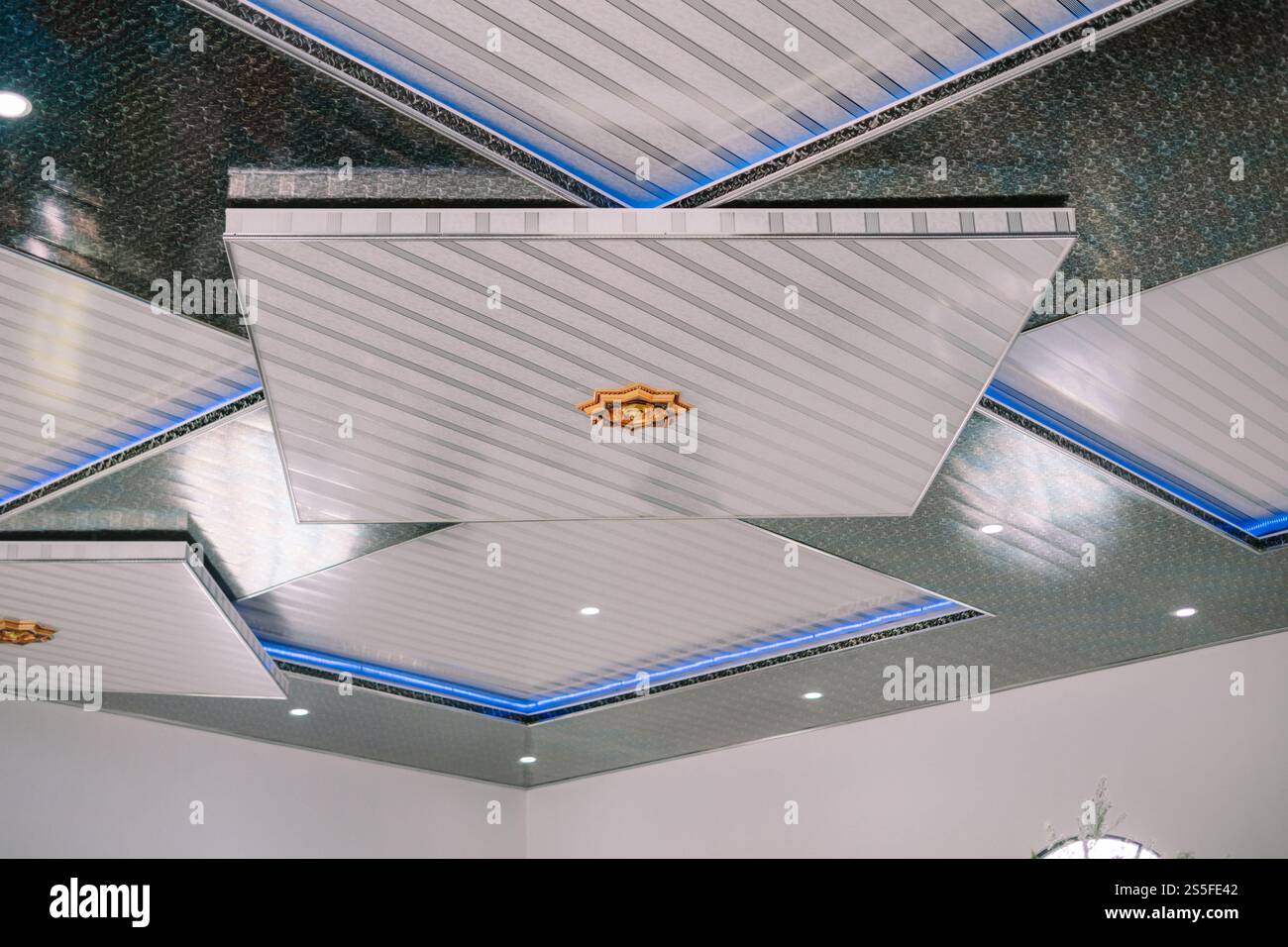 A contemporary ceiling featuring geometric panels, integrated lighting ...