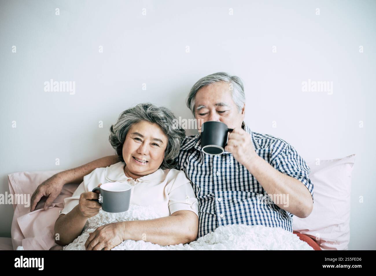 Senior couple laughing while drinking coffee in bedroom Stock Photo - Alamy