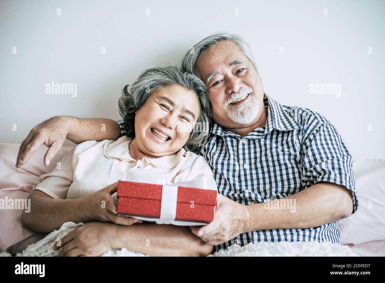 Smiling senior husband making surprise giving gift box to his wife in ...
