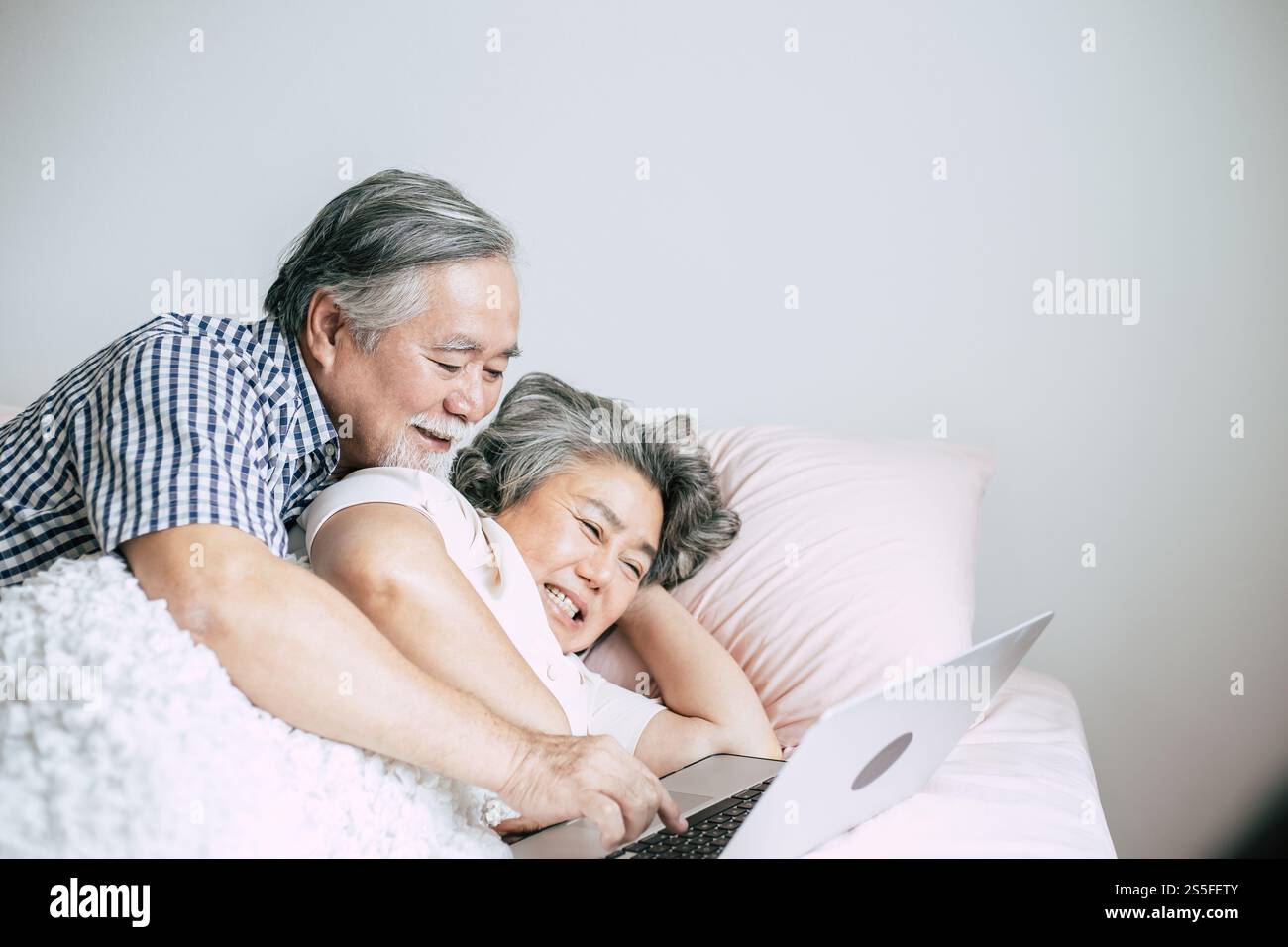Elderly couple using laptop in bedroom Stock Photo - Alamy