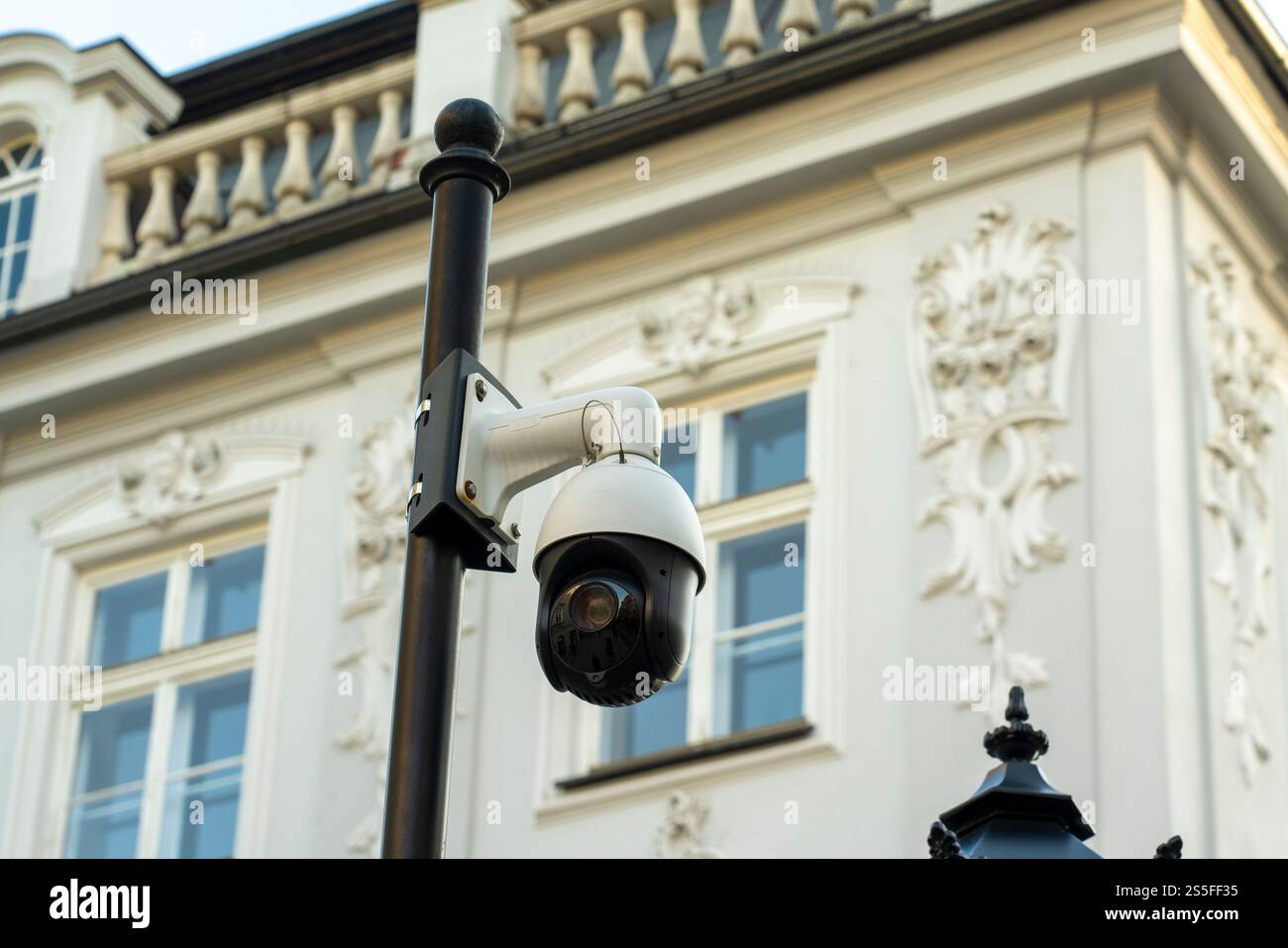 Security camera mounted on a pole in front of an elegant building with ...
