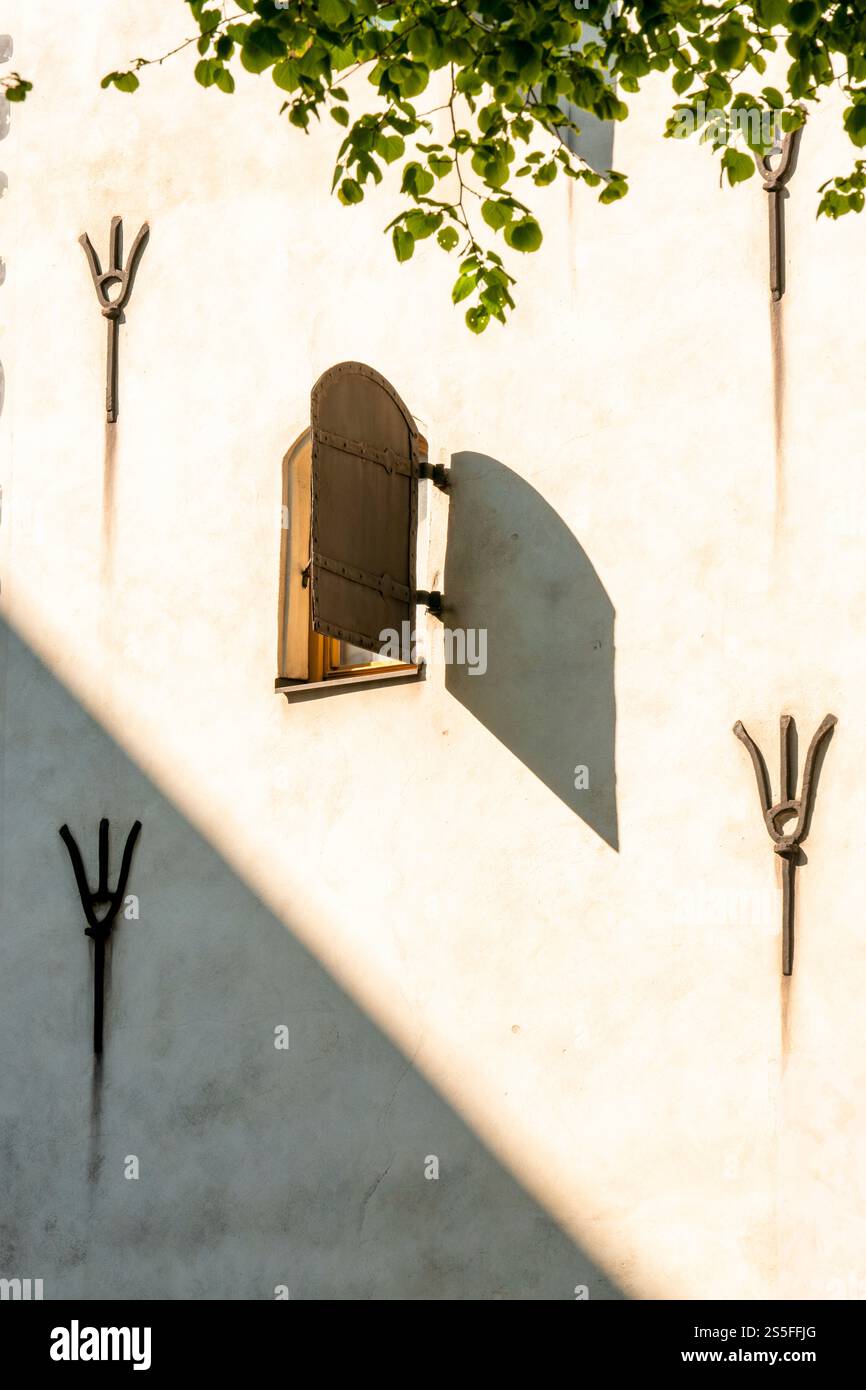 Sunlit wall with an open wooden shutter casting a shadow, accentuated ...