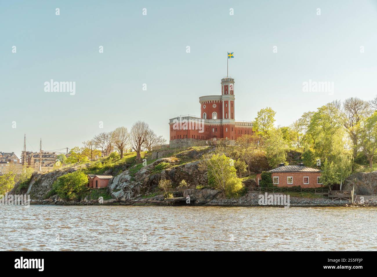 Red brick Stockholm Castle with a flag tower on an island against a ...
