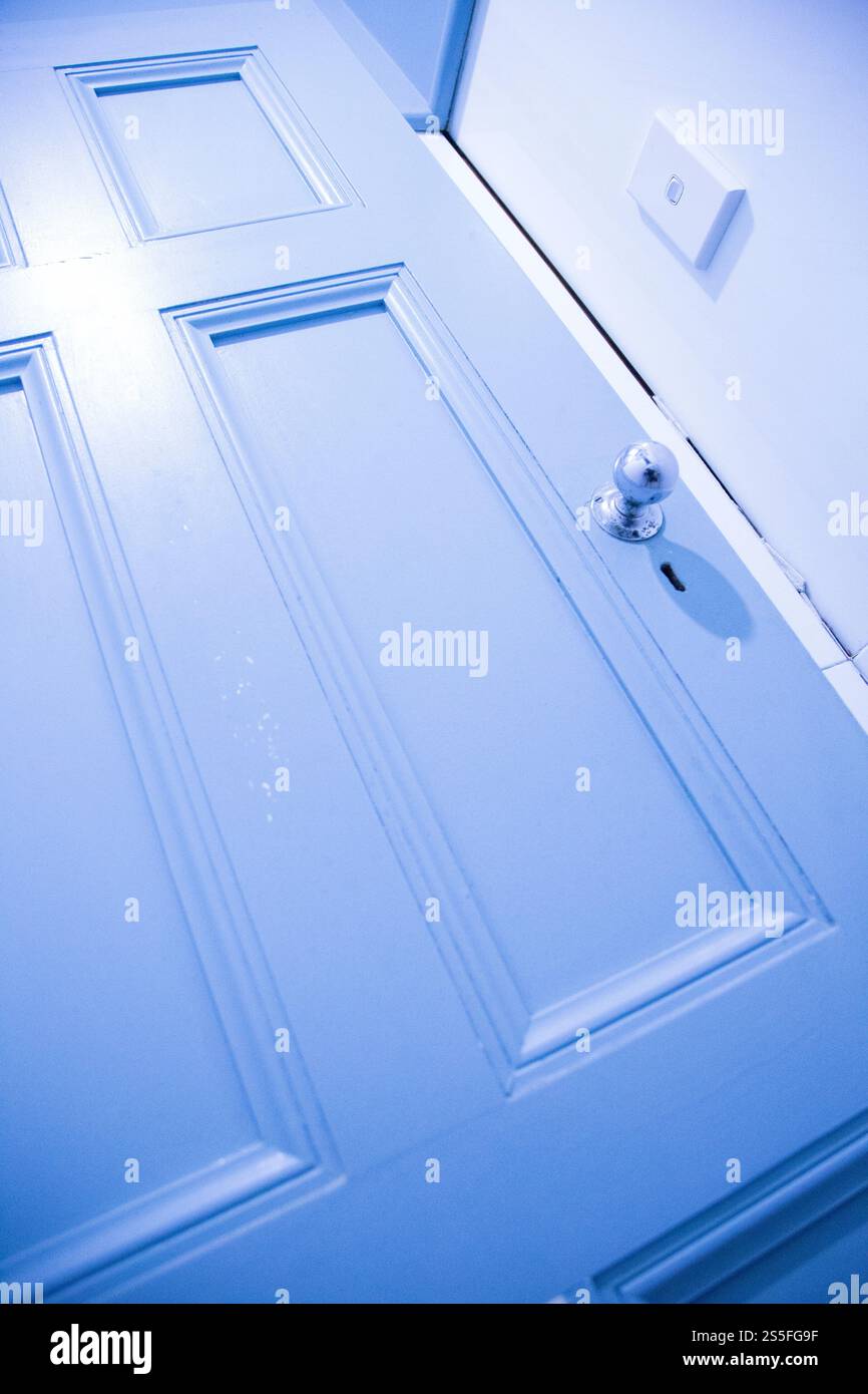 Blue door partially ajar in a white wall with a silver doorknob and ...