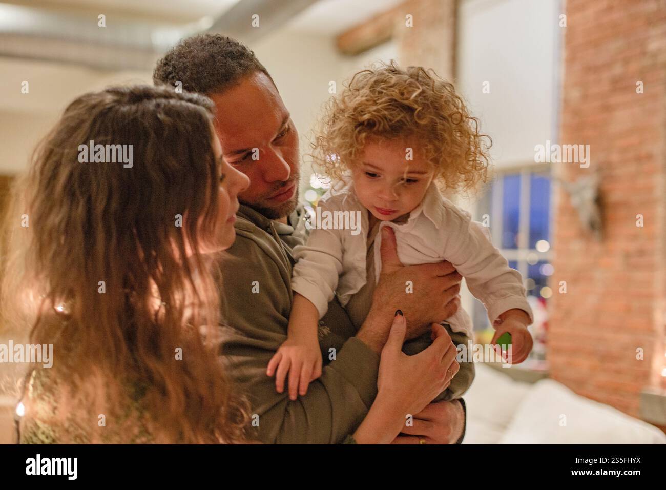 Affectionate parents embrace ir toddler curly hair cozy home setting hi ...