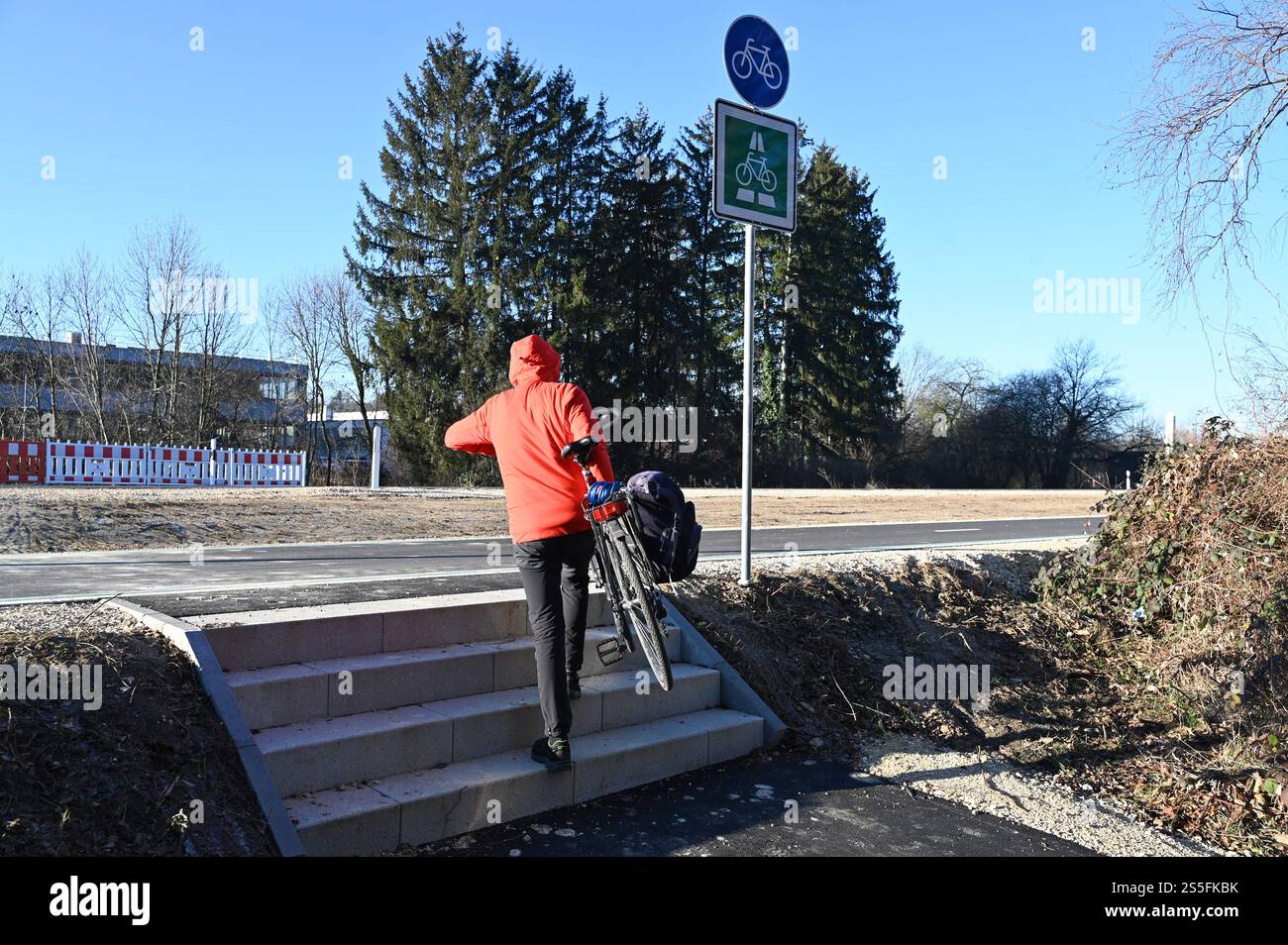 14 January 2025, Baden-Württemberg, Süßen: A cyclist carries his bike ...
