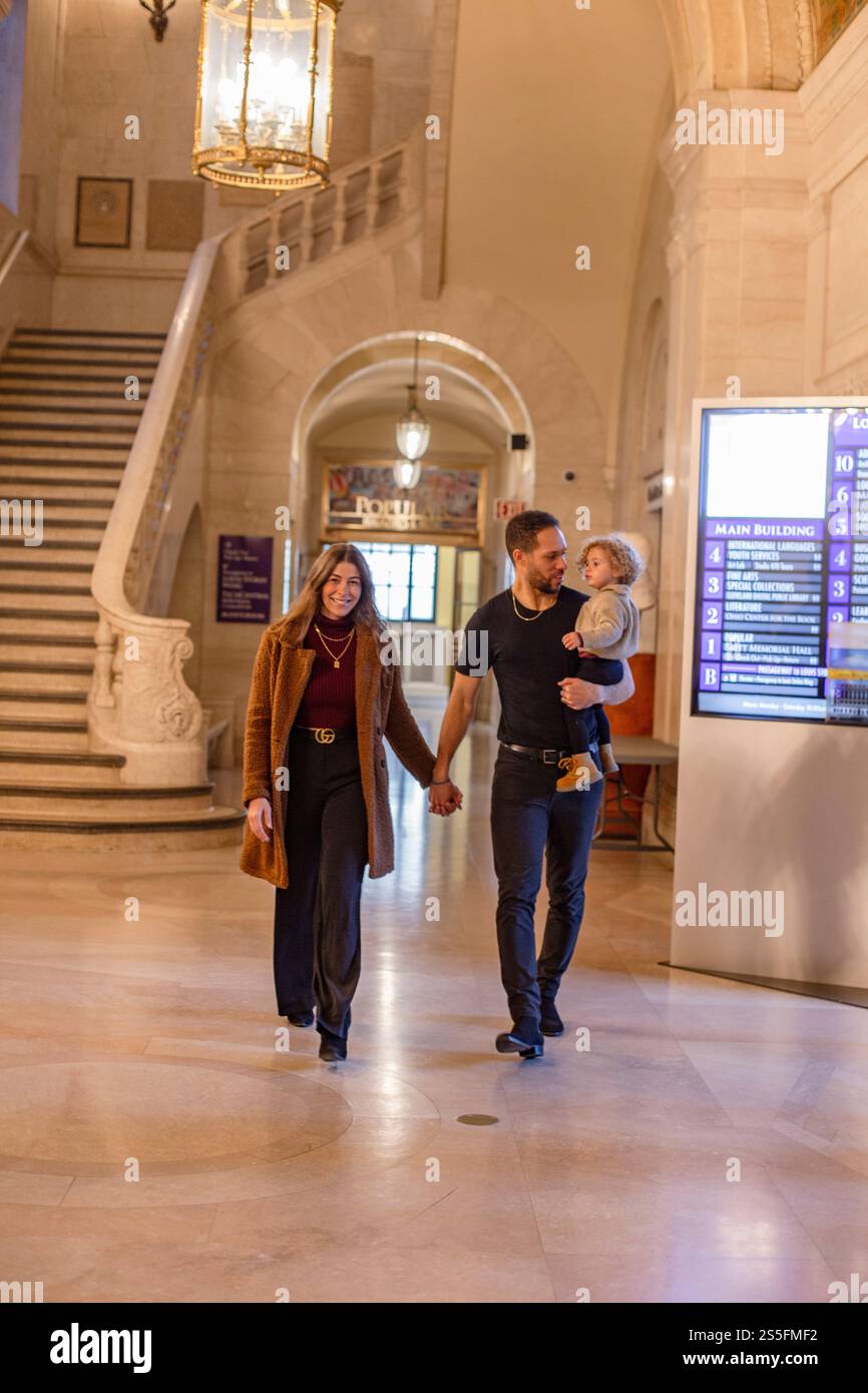 Family exploring a grand interior space with a man carrying a child and ...