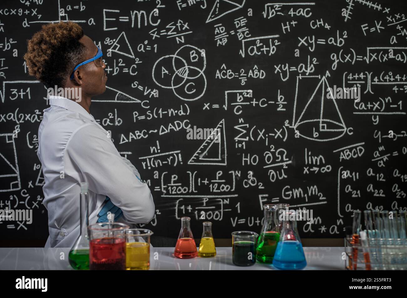 Scientists wear glasses and fold their arms to see the formula on the blackboard in the ...