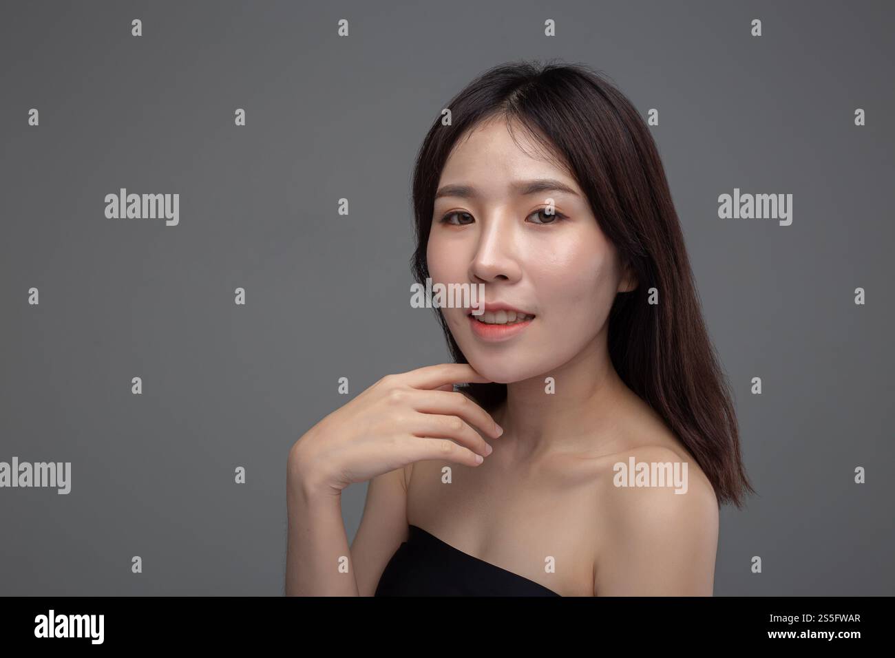 Woman wearing a black strapless dress and hands touching the chin Stock ...