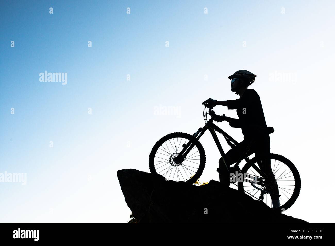 Silhouette of the athlete standing on the rock with bicycle Stock Photo ...