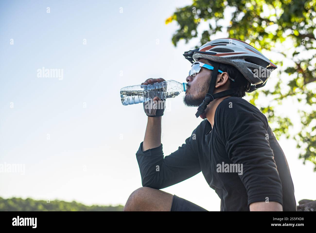 Mountain cyclists stand on the top of the mountain and drink a bottle ...