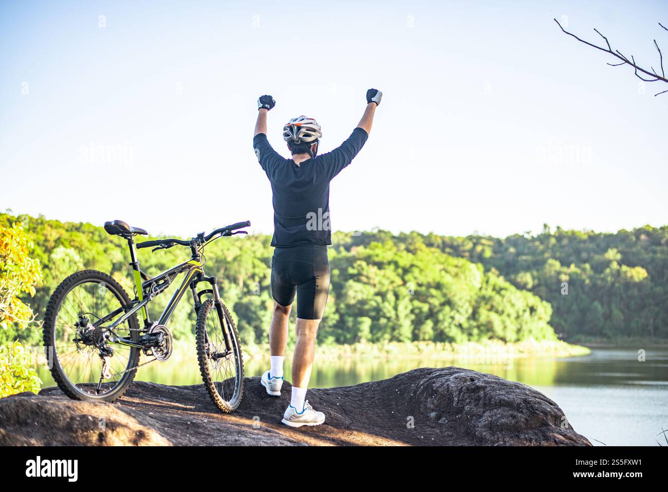 Mountain cyclists stand on the top of the mountain with a bicycle and ...