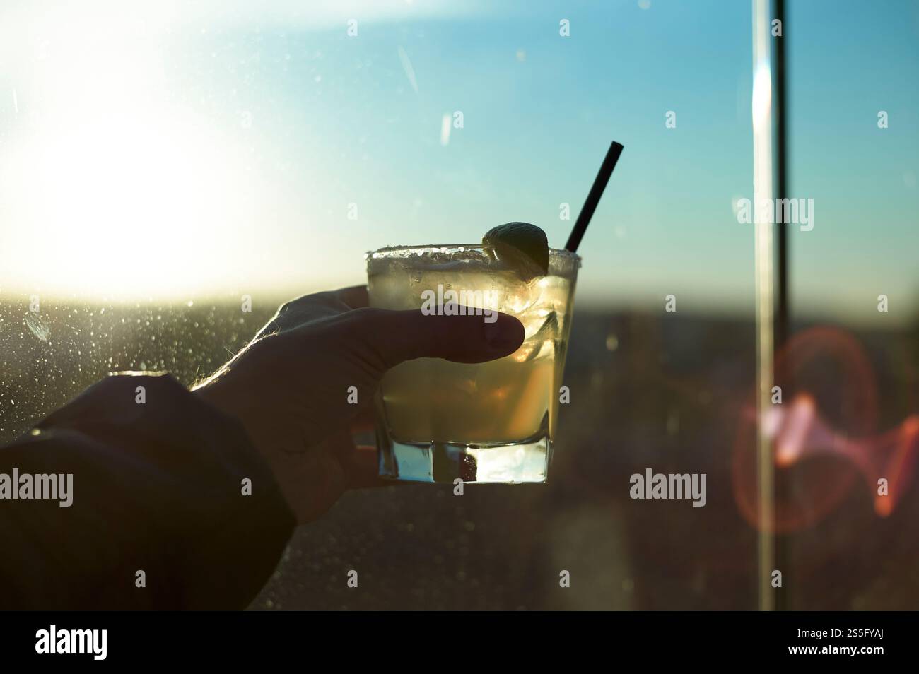Mans hand holding cocktail glass sunset backdrop hi-res stock ...