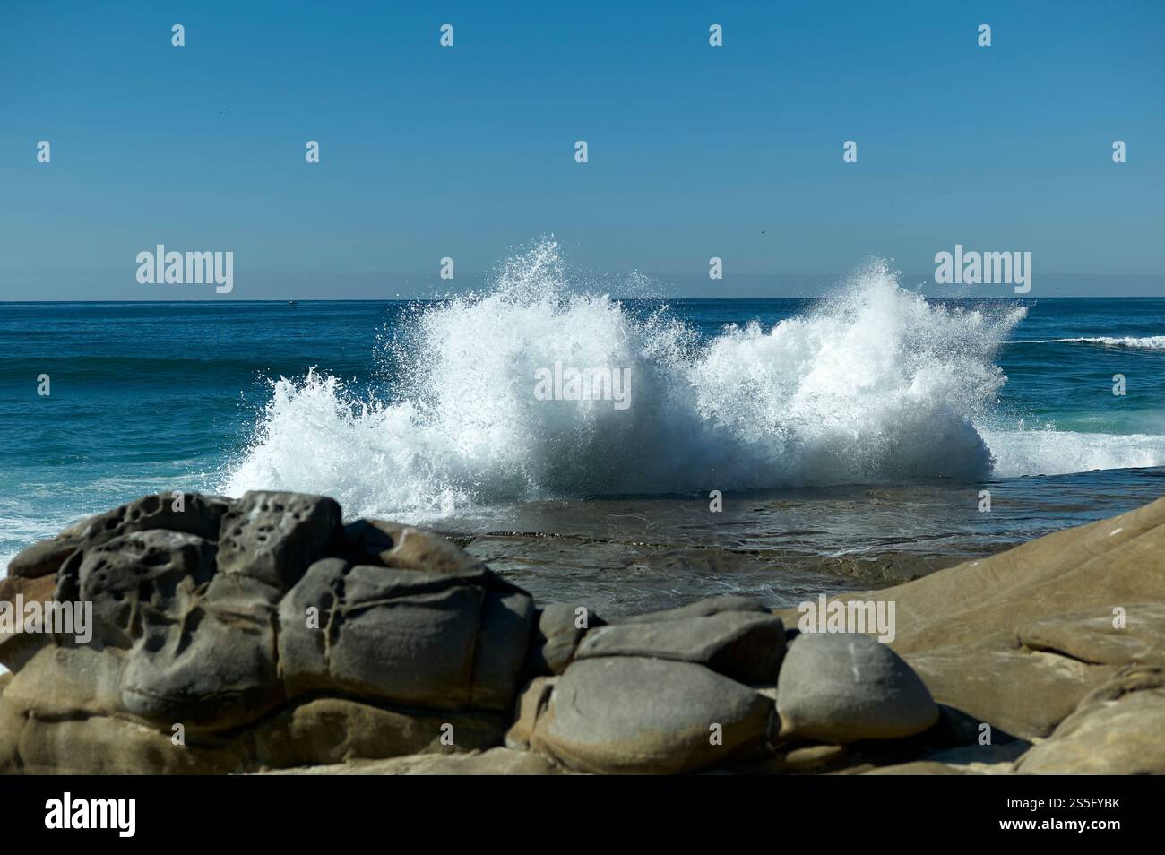 Ocean wave crashing against rocks with a clear blue sky, New Orleans, USA Stock Photo - Alamy