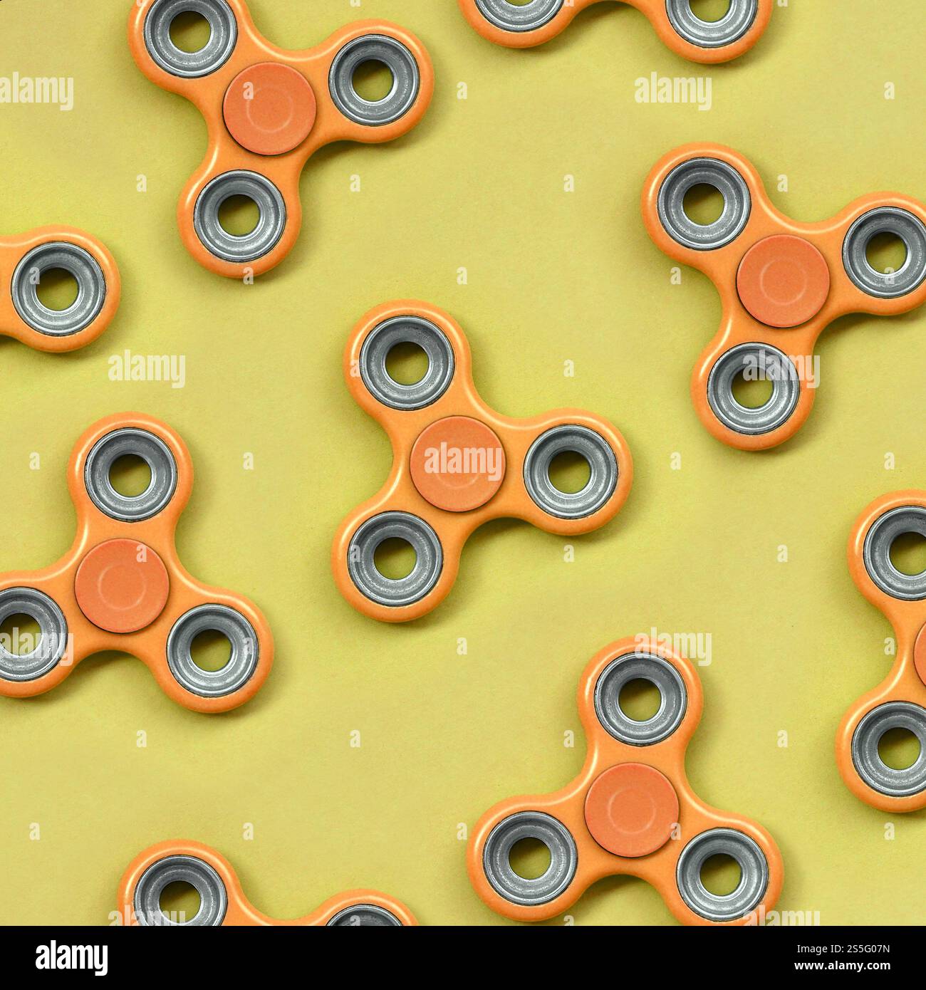 Many orange fidget spinners lies on texture background of fashion ...