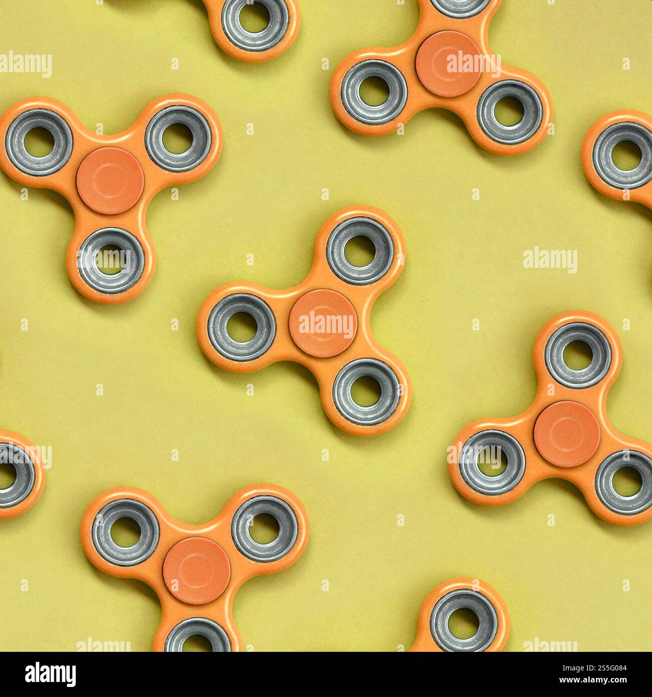 Many orange fidget spinners lies on texture background of fashion ...