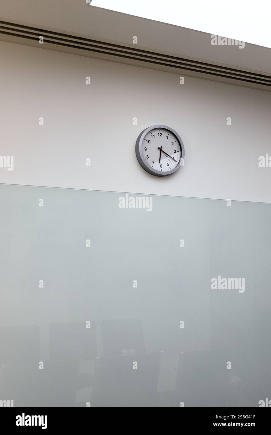 clock on wall of empty office hall shows twenty past six after end of ...