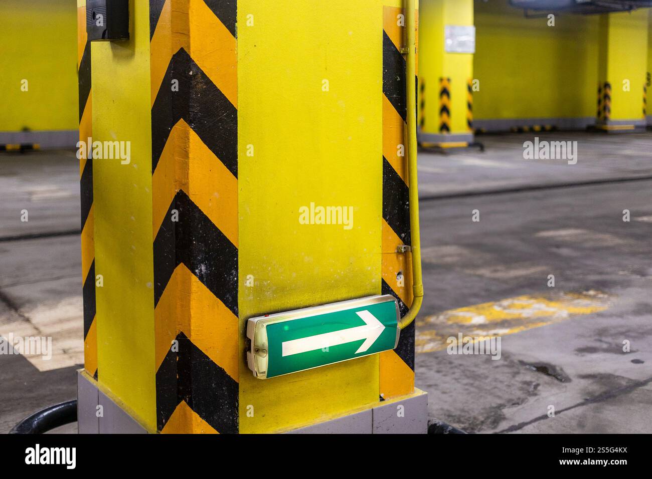 green traffic direction arrow sign on yellow underground parking post ...