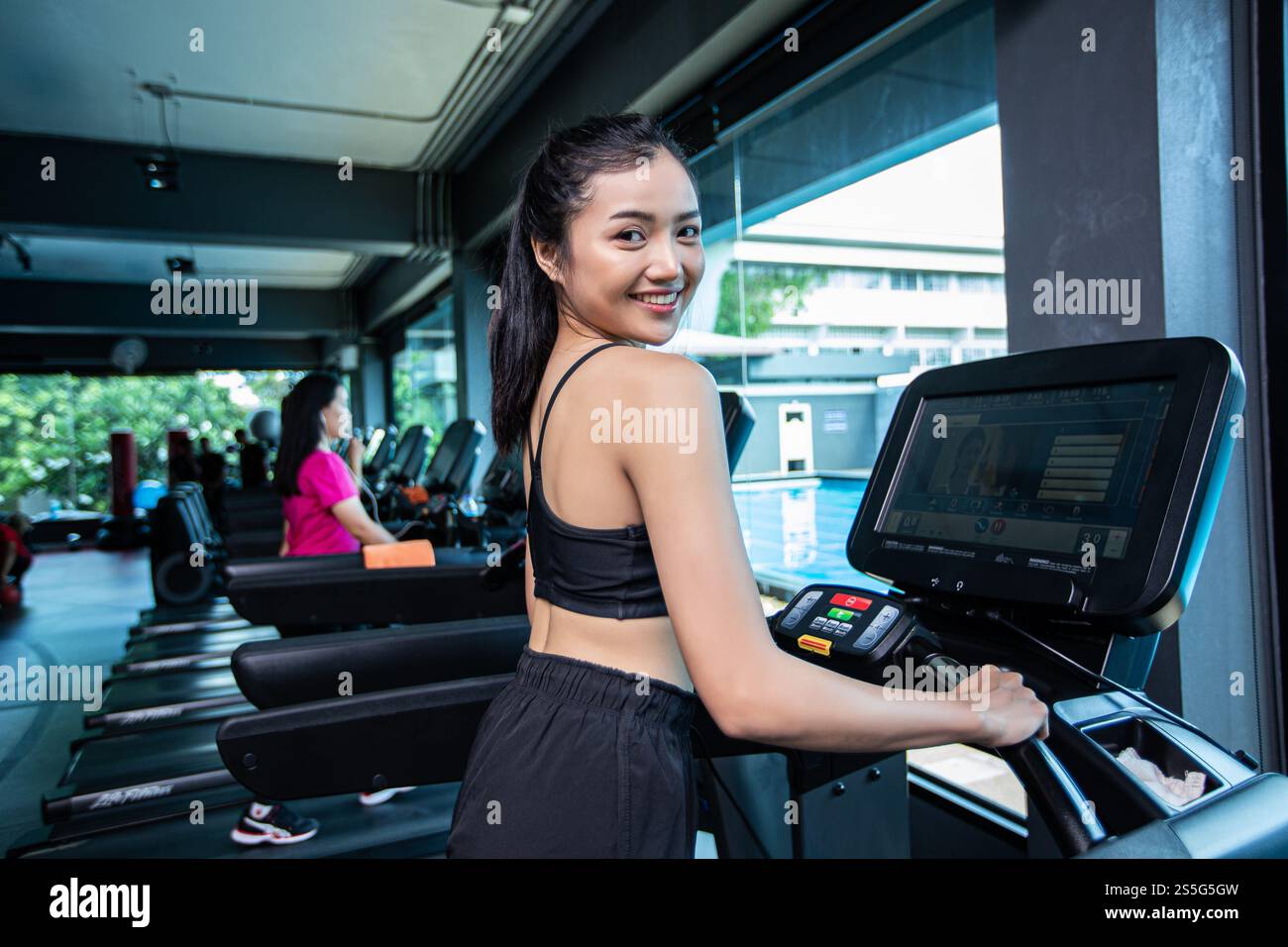 Beautiful fitness women prepare for running at the treadmill in the gym ...