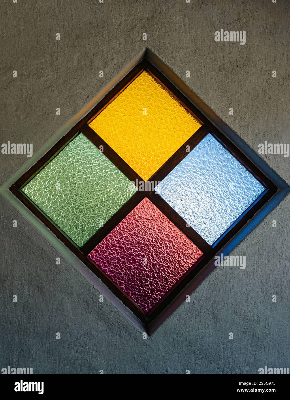 rhombus shape stained glass window is embedded in gray wall rough ...